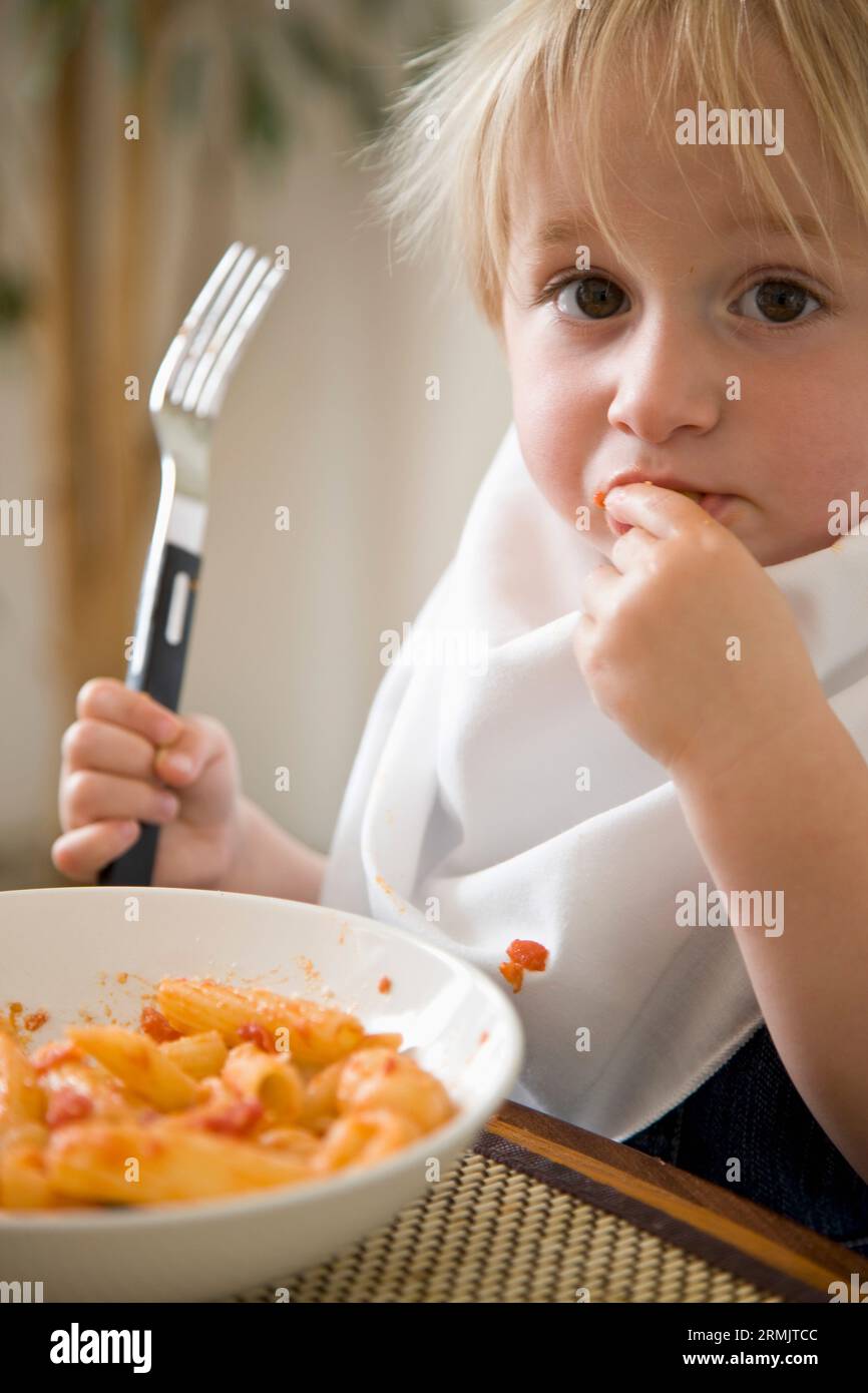 Portrait of young blonde boy eating pasta Stock Photo - Alamy