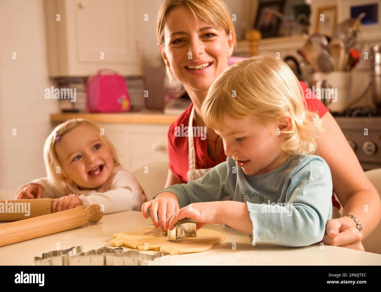 Portrait of young blonde woman with little girls smiling and baking ...
