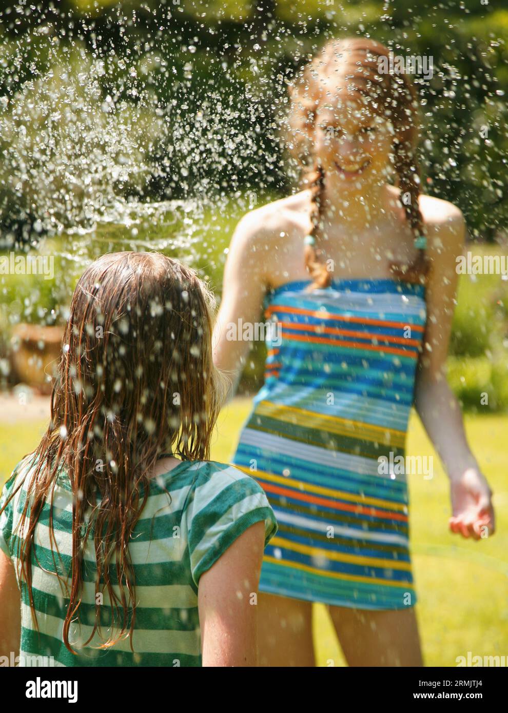 Portrait of teenager spraying girl with water Stock Photo - Alamy