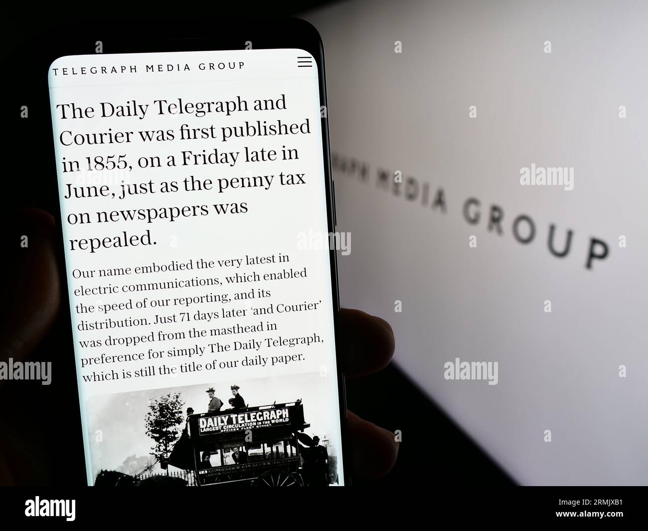 Person holding mobile phone with web page of company Telegraph Media ...