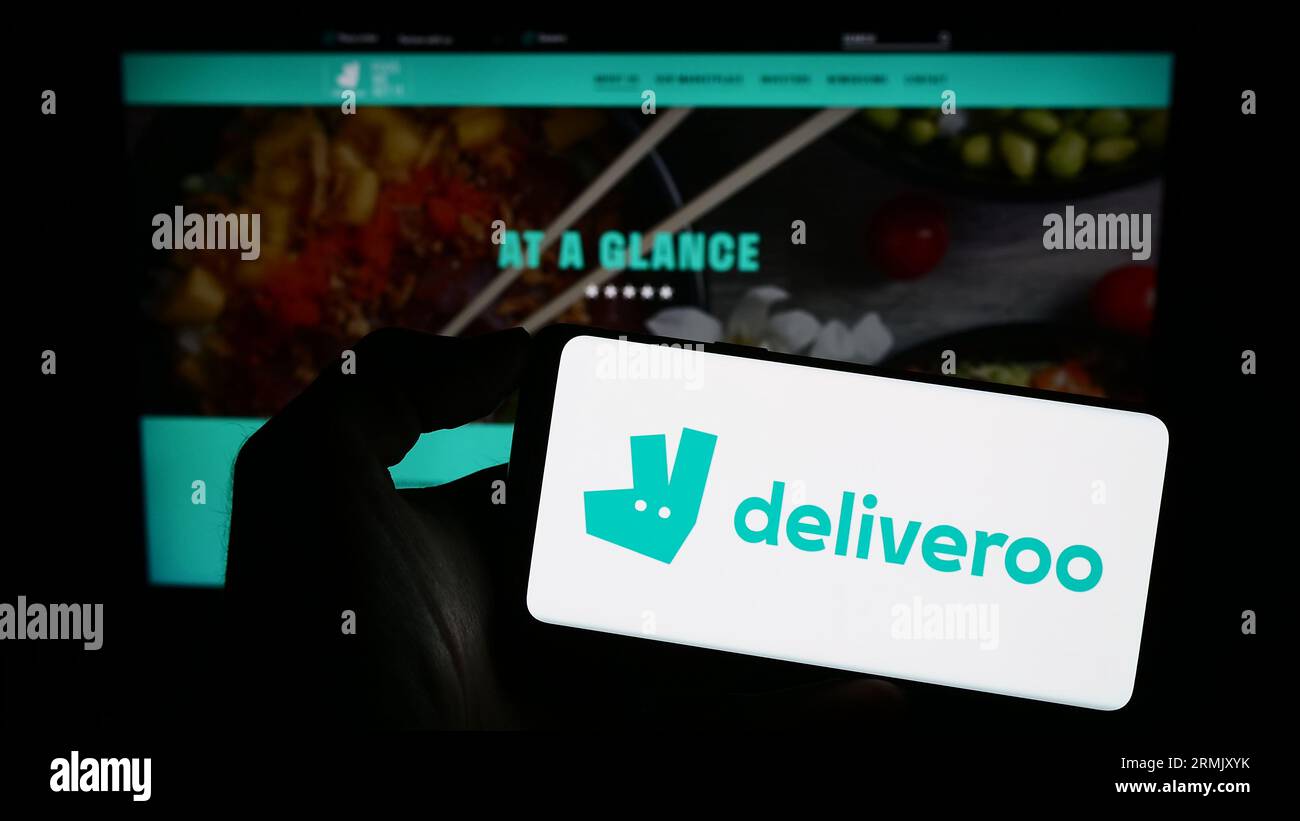 Person holding cellphone with logo of food delivery company Deliveroo ...