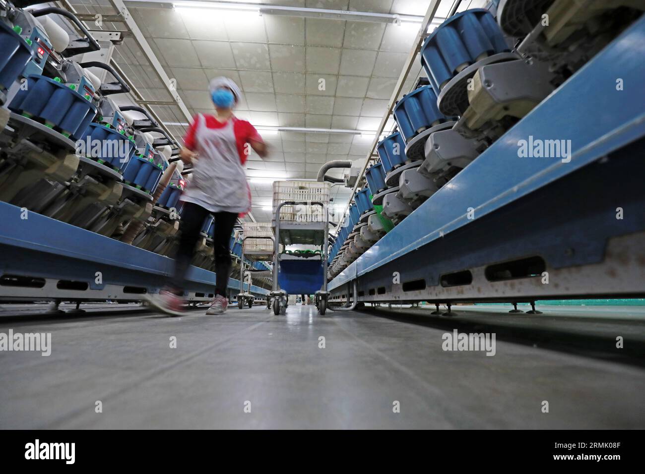 The female worker is busy on the production line in a spinning factory ...