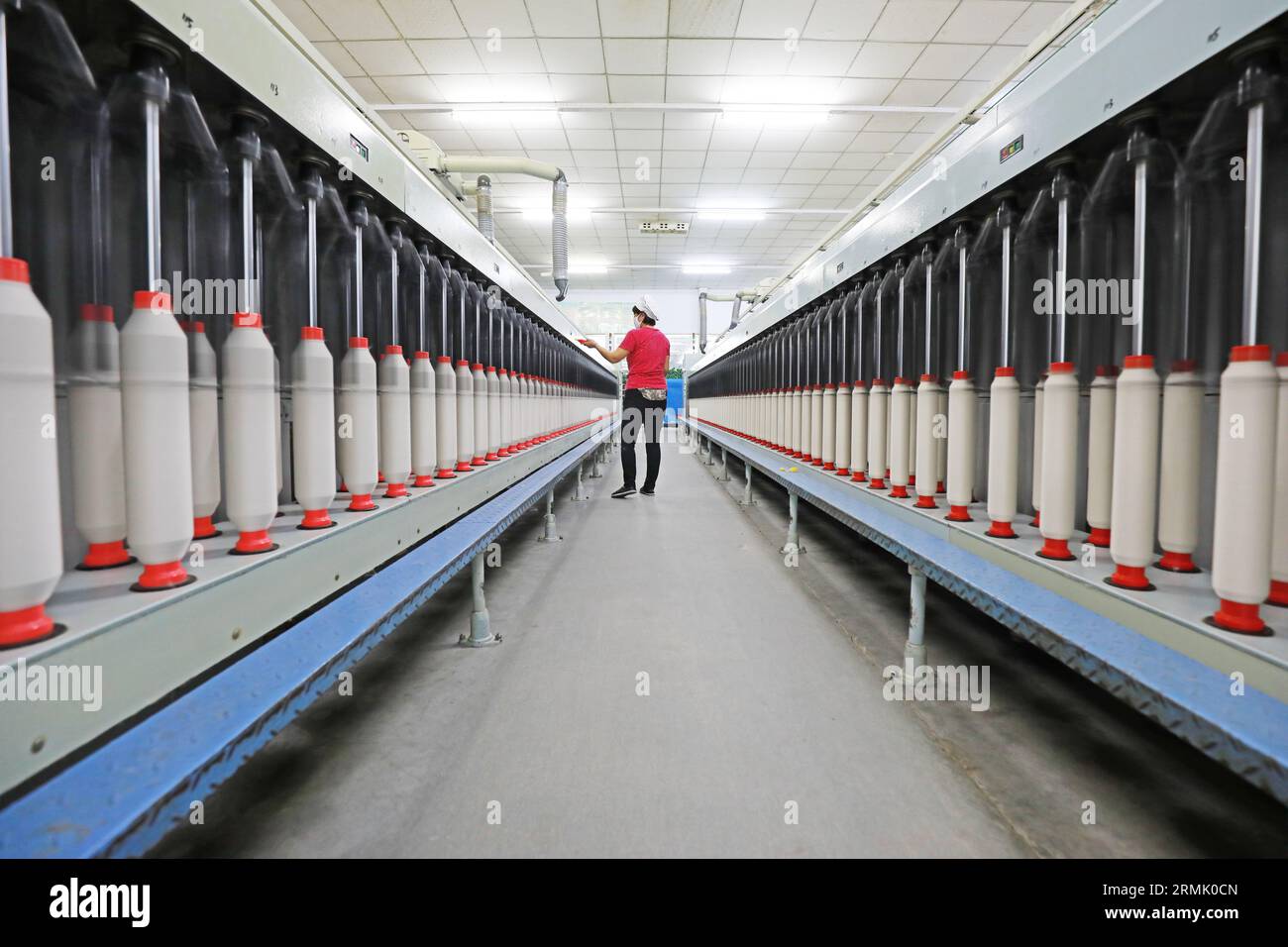 The female worker is busy on the production line in a spinning factory ...