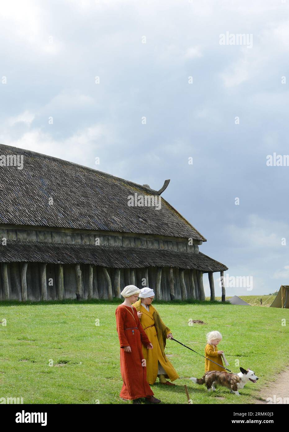 Women and a little girl dressed in traditional Viking clothes walk by ...