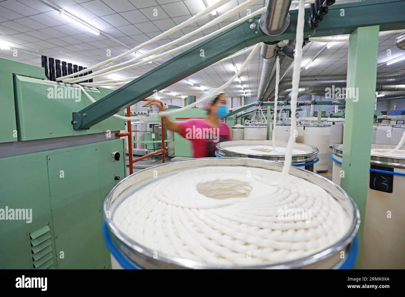 The female worker is busy on the production line in a spinning factory ...