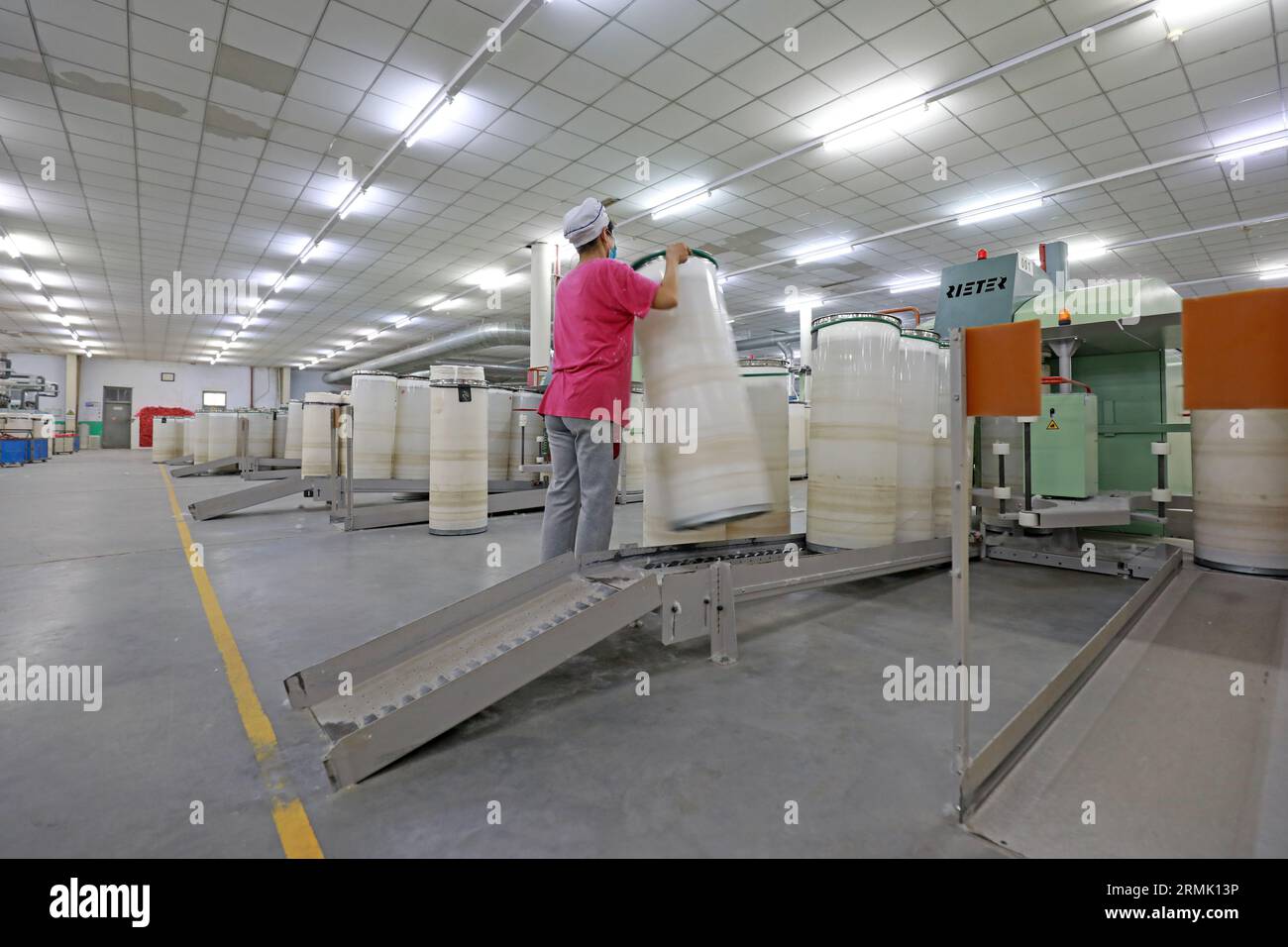 The female worker is busy on the production line in a spinning factory ...