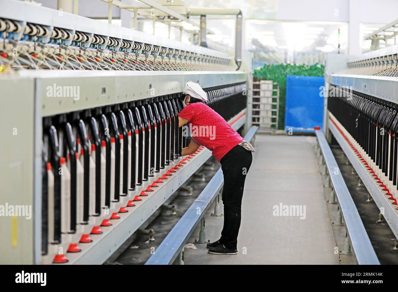 The female worker is busy on the production line in a spinning factory ...