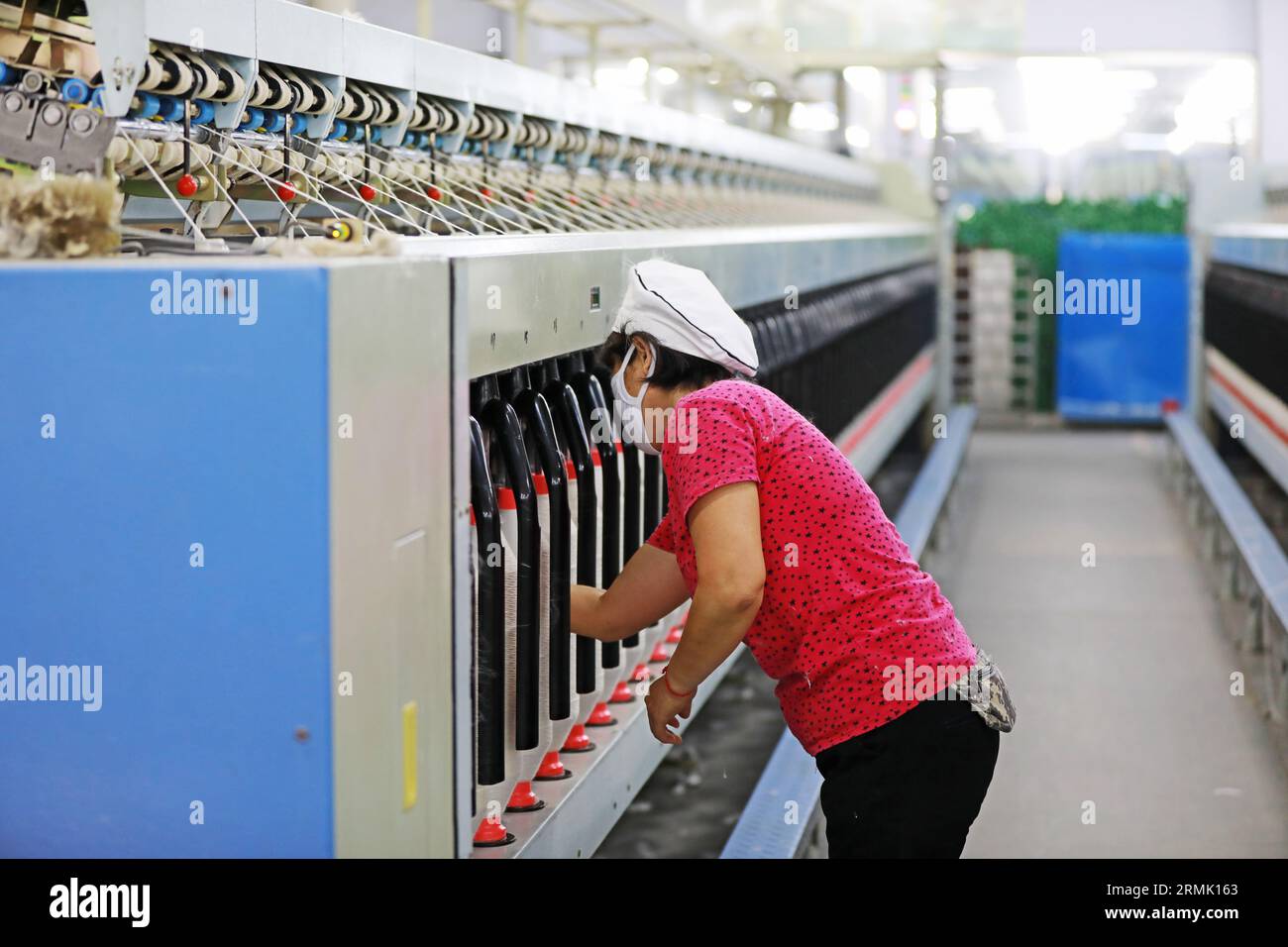 The female worker is busy on the production line in a spinning factory ...