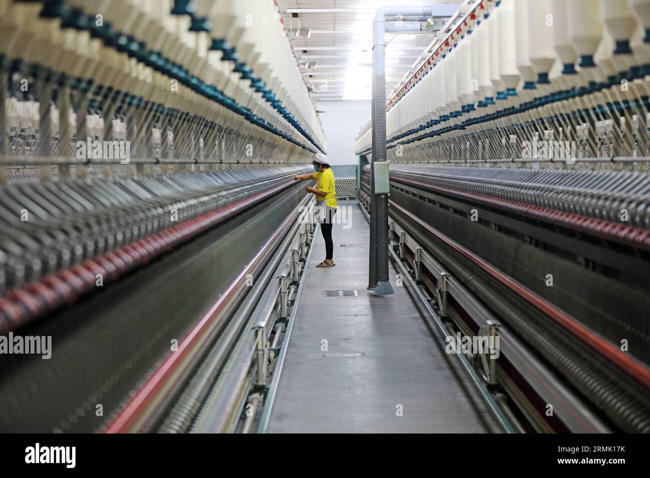 The female worker is busy on the production line in a spinning factory ...