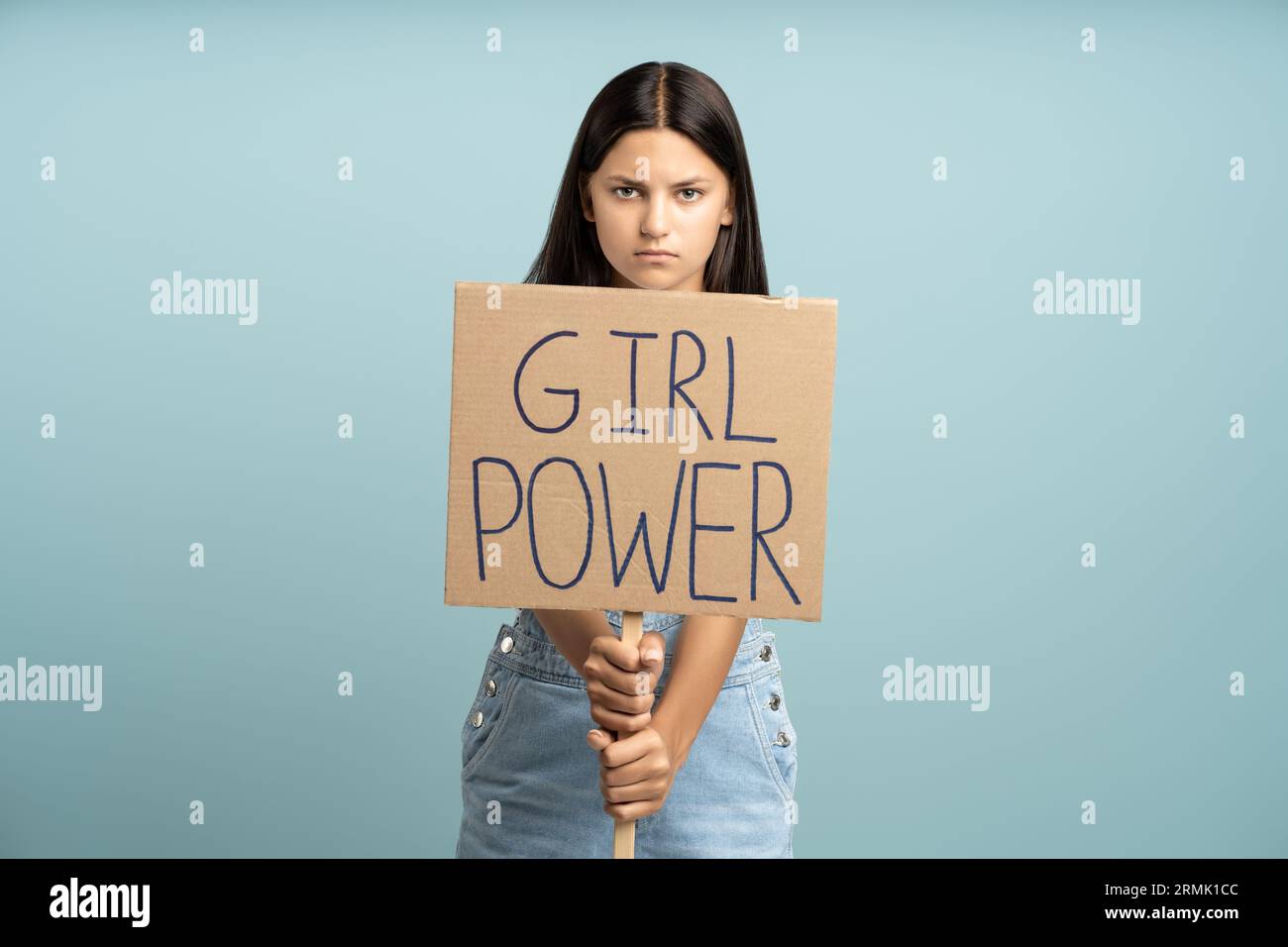 Serious confident teen girl showing holding girl power poster on blue ...