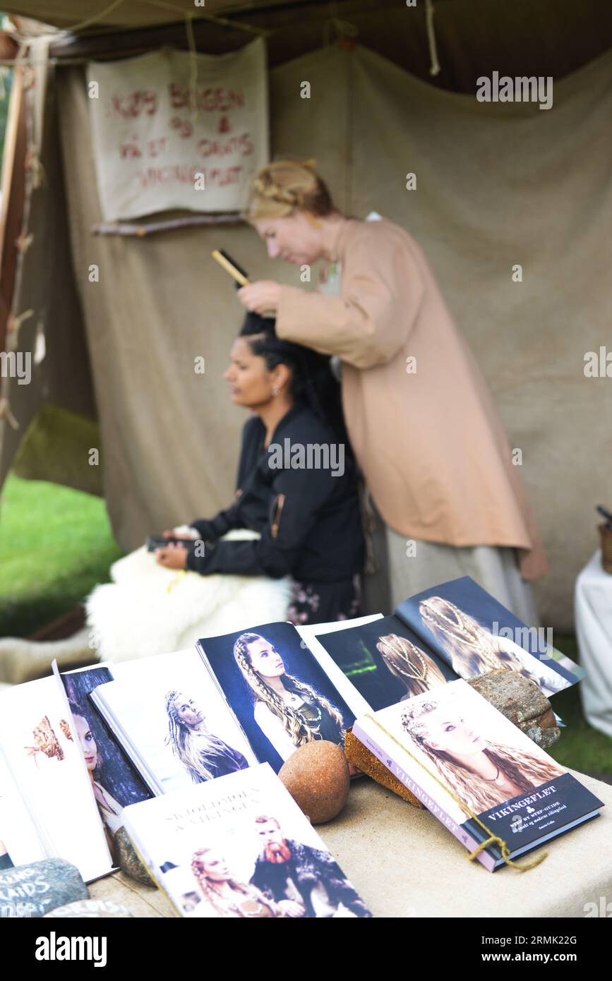 A woman getting her hair styled in a traditional Viking style ...