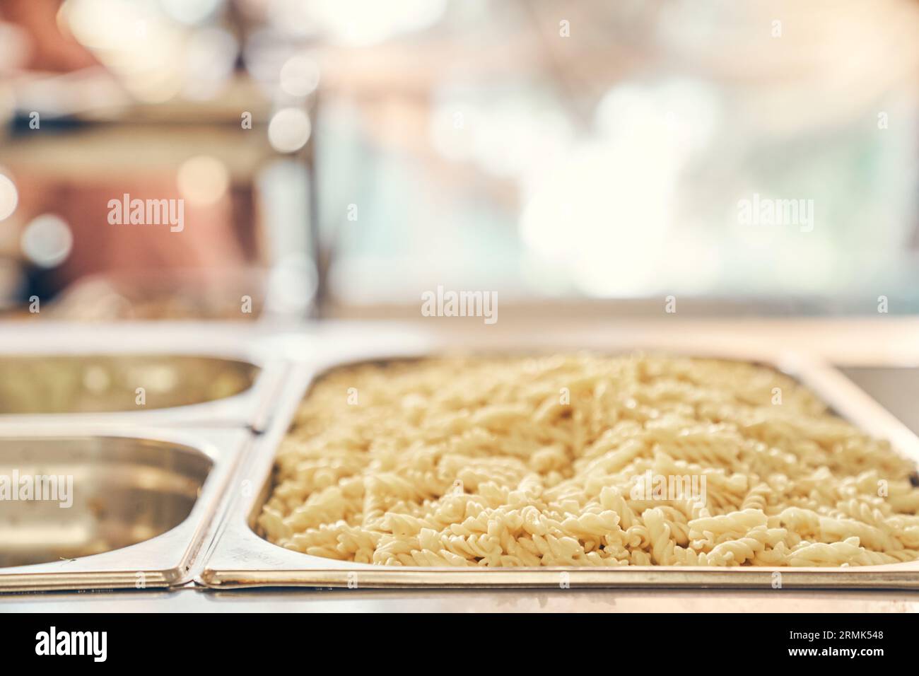 Close-up of boiled pasta, lying in a metal tray at the distribution in ...