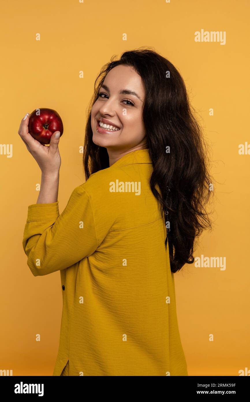 Gorgeous long-haired young woman with a fresh red apple in her hand ...
