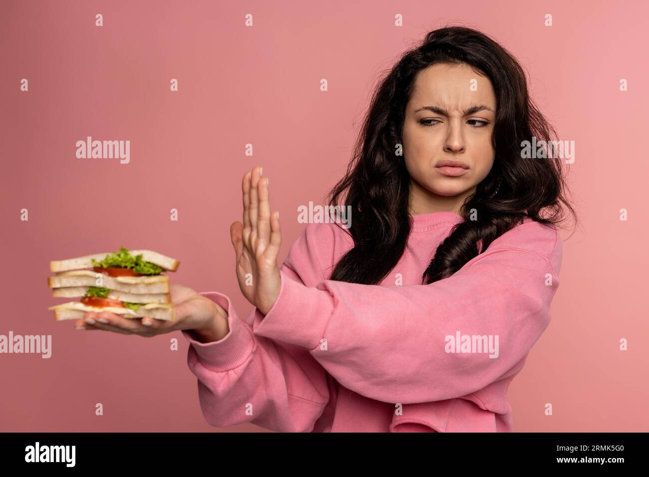 Displeased young dark-haired female showing her food aversion during ...