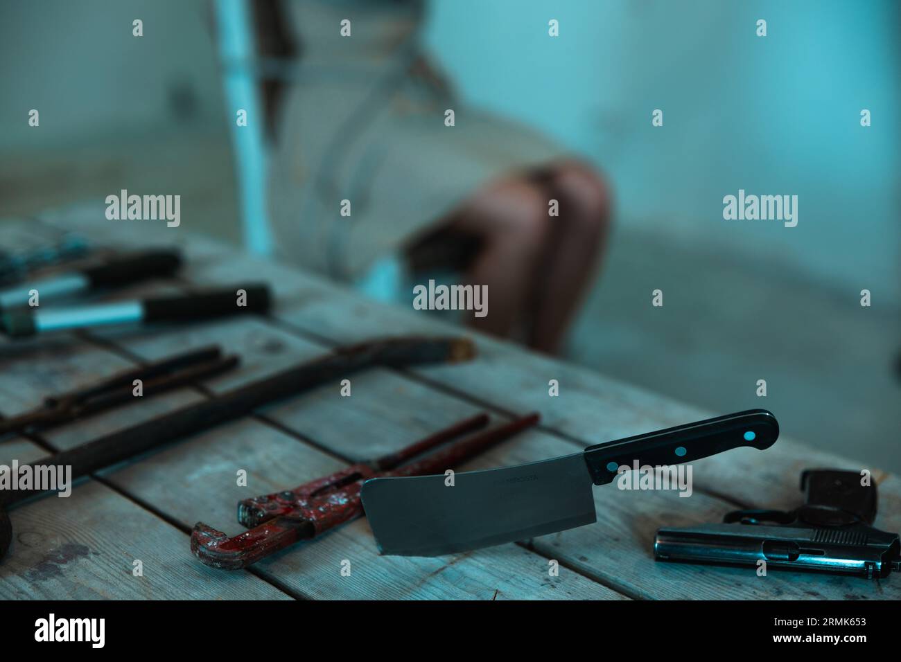 Weapons on the table. Kidnapped woman sitting on a chair and tied with ...