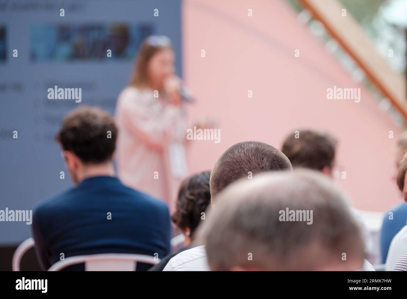 Back view of anonymous crowd of people gathering together and listening ...