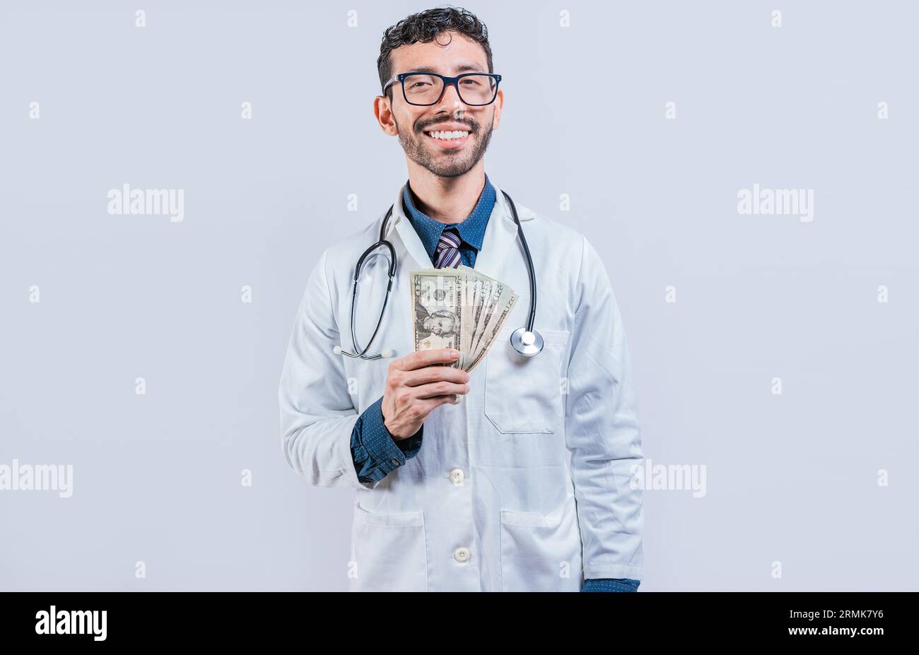 Happy young doctor holding money isolated. Handsome doctor showing ...