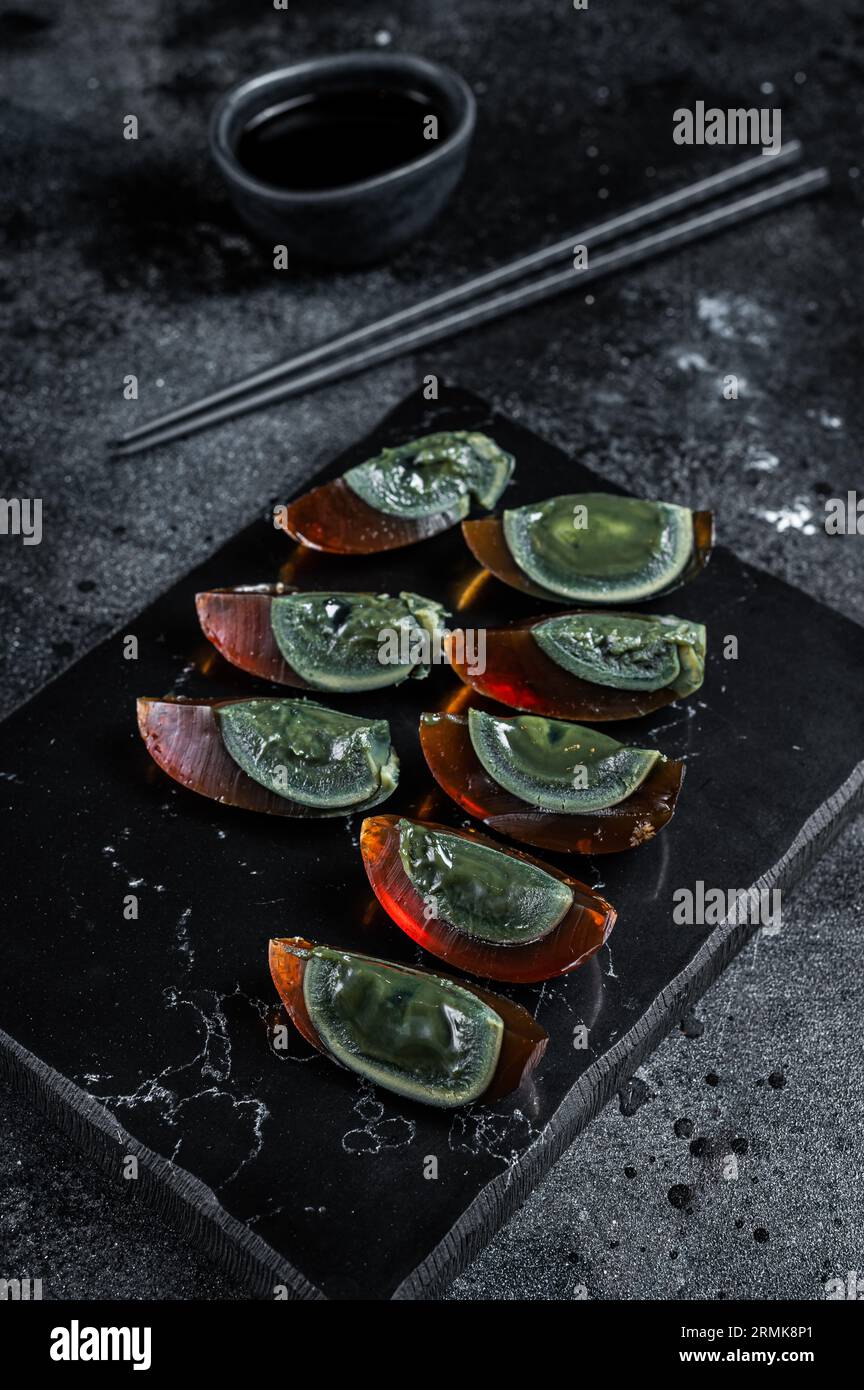 Chinese Century eggs, black egg is cut showing dark yolk. Black ...