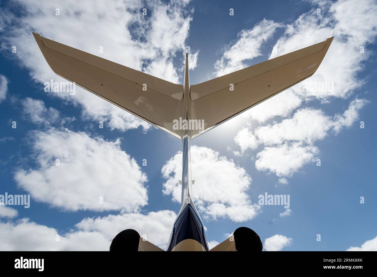Tail of a private jet aircraft, blue and white against a cloudy blue ...