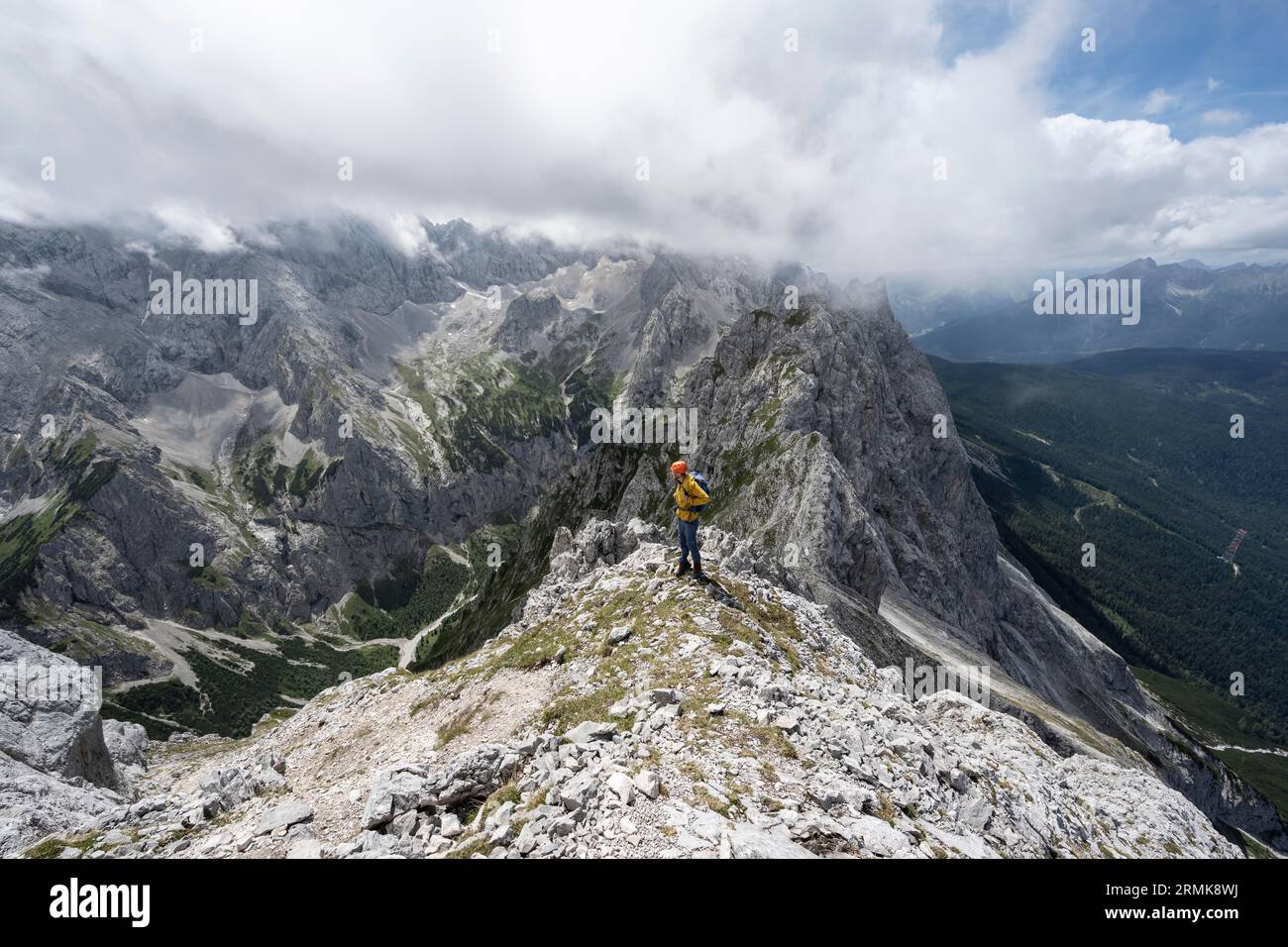 Mountaineer at the summit of the Waxenstein, view over rocky and narrow ...
