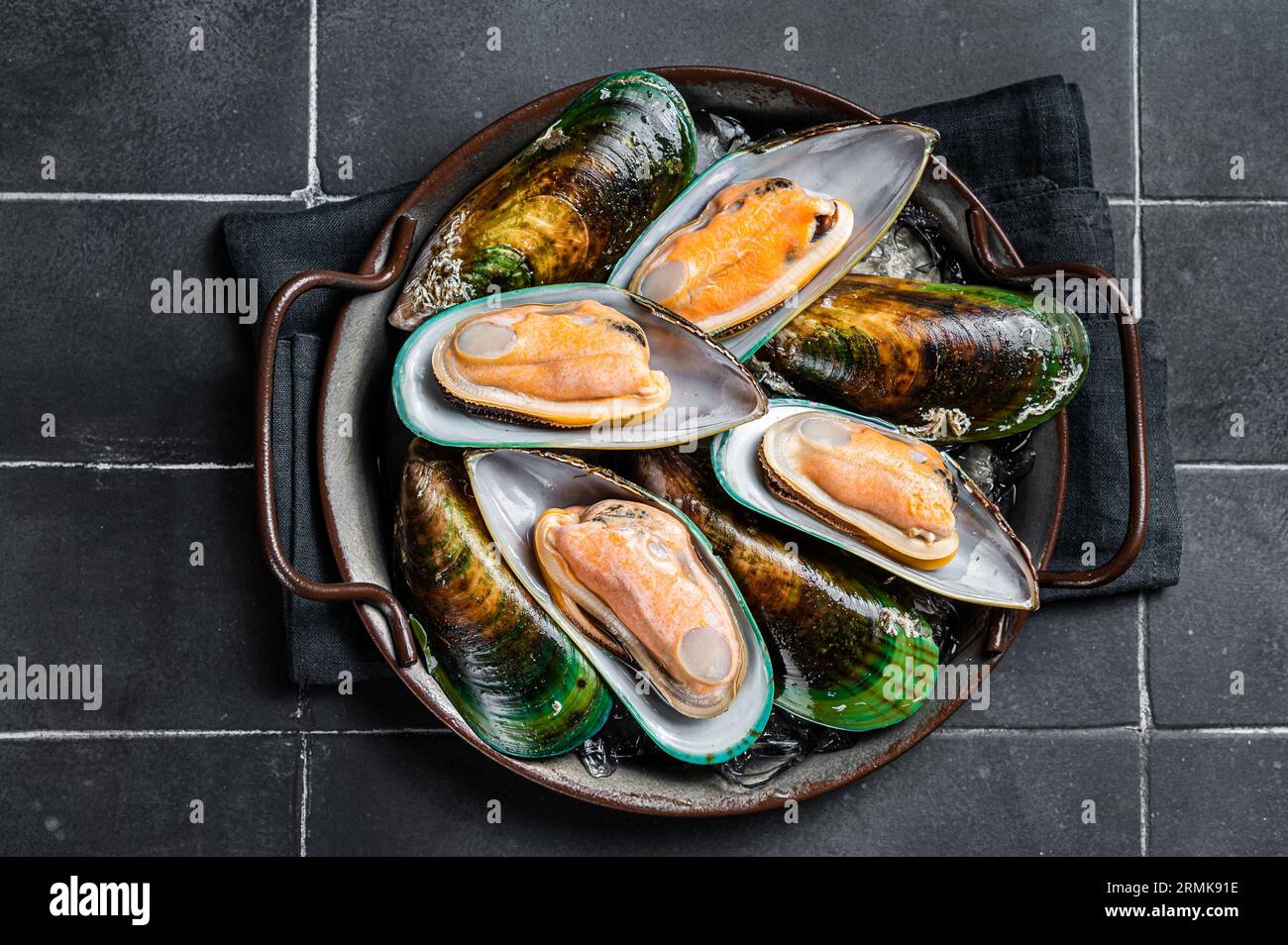 Large green mussels in shells on tray with ice. Black background. Top ...