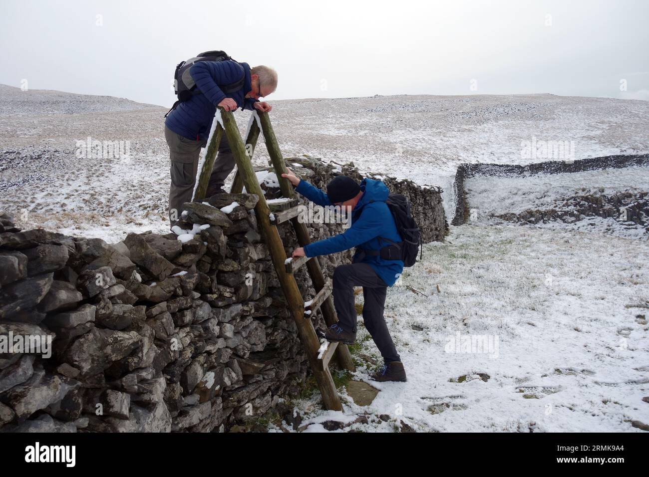 Two Elderly Men (Hikers) Climbing Wooden Ladder Stile in Snow over Dry ...