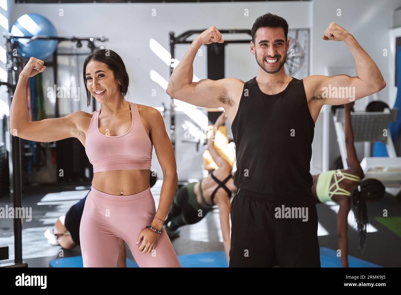 Fitness people showing their arm muscles after training in the gym ...