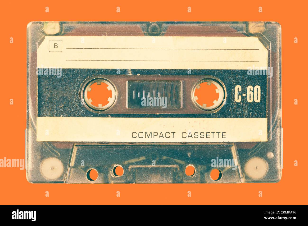Vintage old audio compact cassette in front of an orange background ...