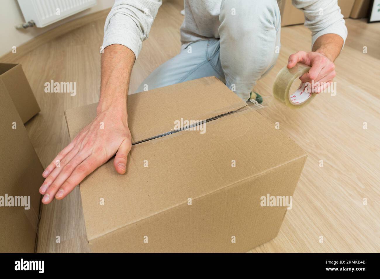Close up male sealing cardboard box with adhesive tape Stock Photo - Alamy