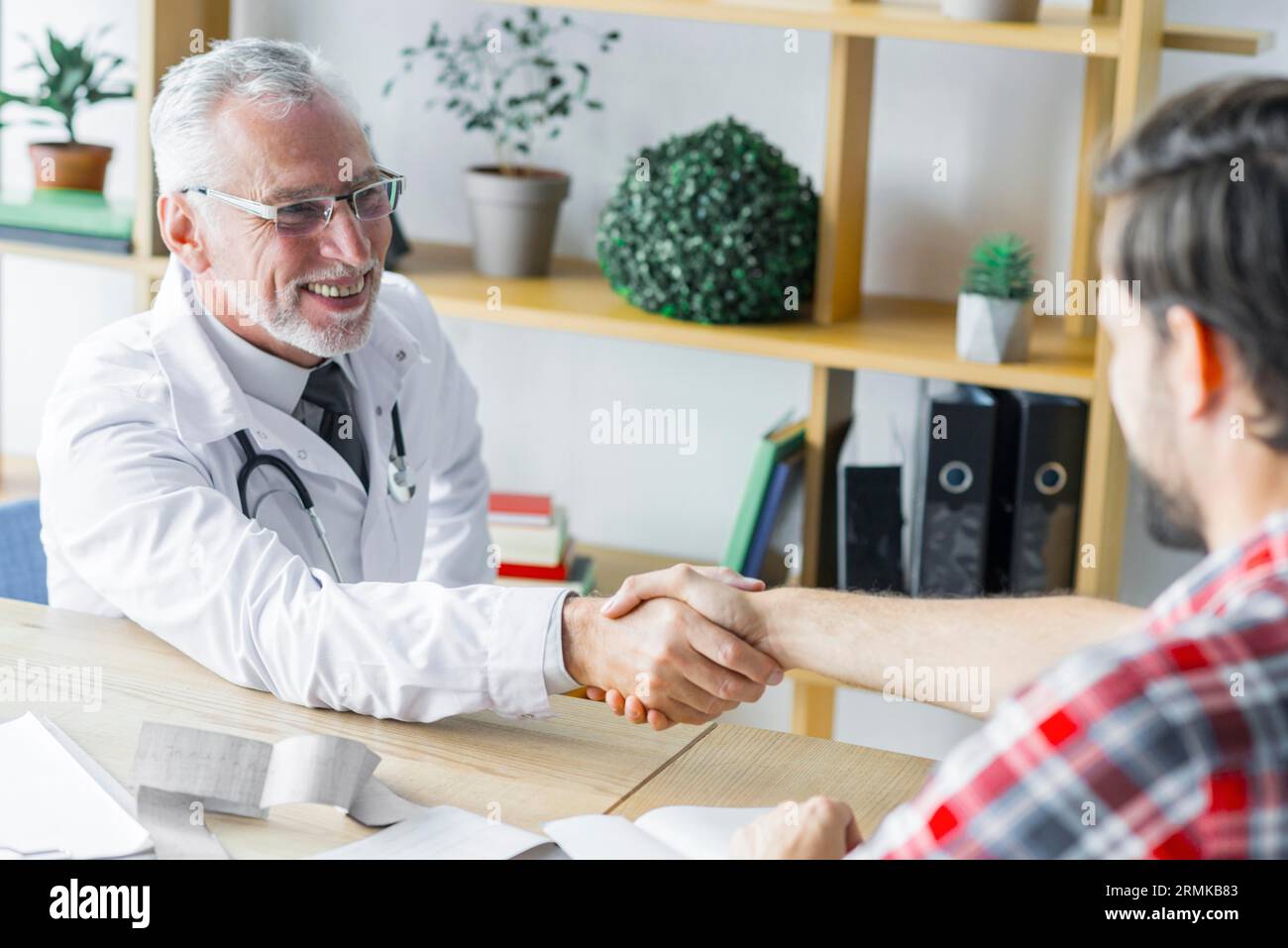 Cheerful doctor shaking hand patient Stock Photo - Alamy