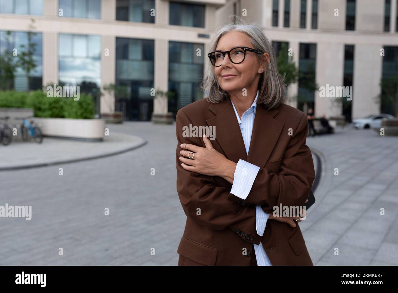 charming successful senior woman with gray hair and glasses is dressed ...