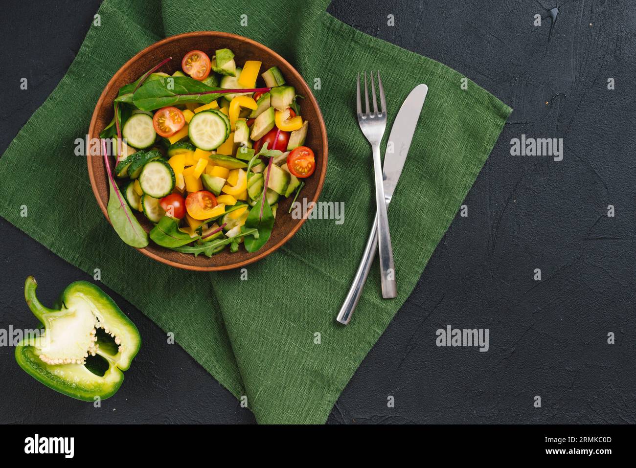 Halved bell pepper mixed vegetable salad green napkin black concrete ...