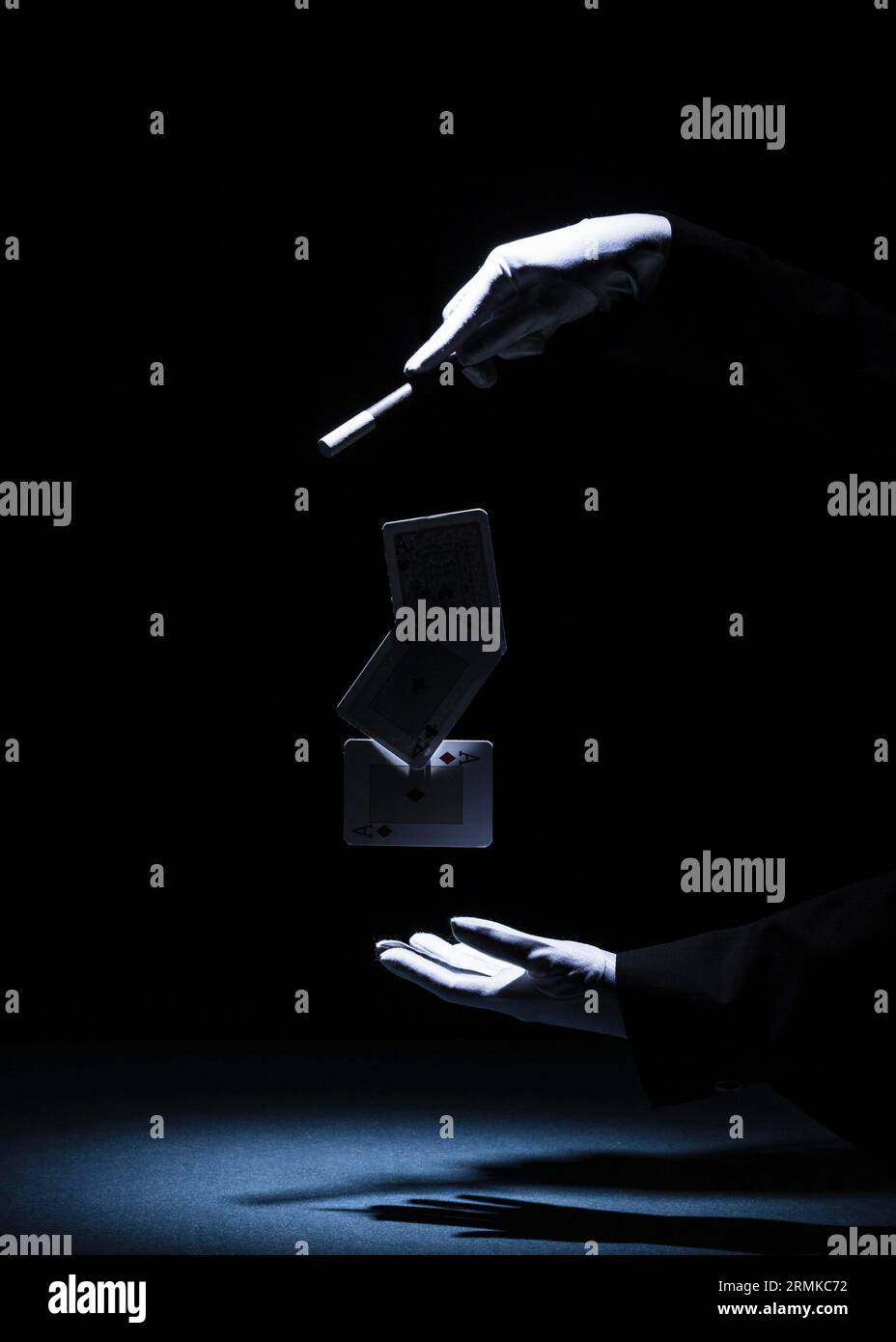 Magician performing trick with magic wand against black background ...