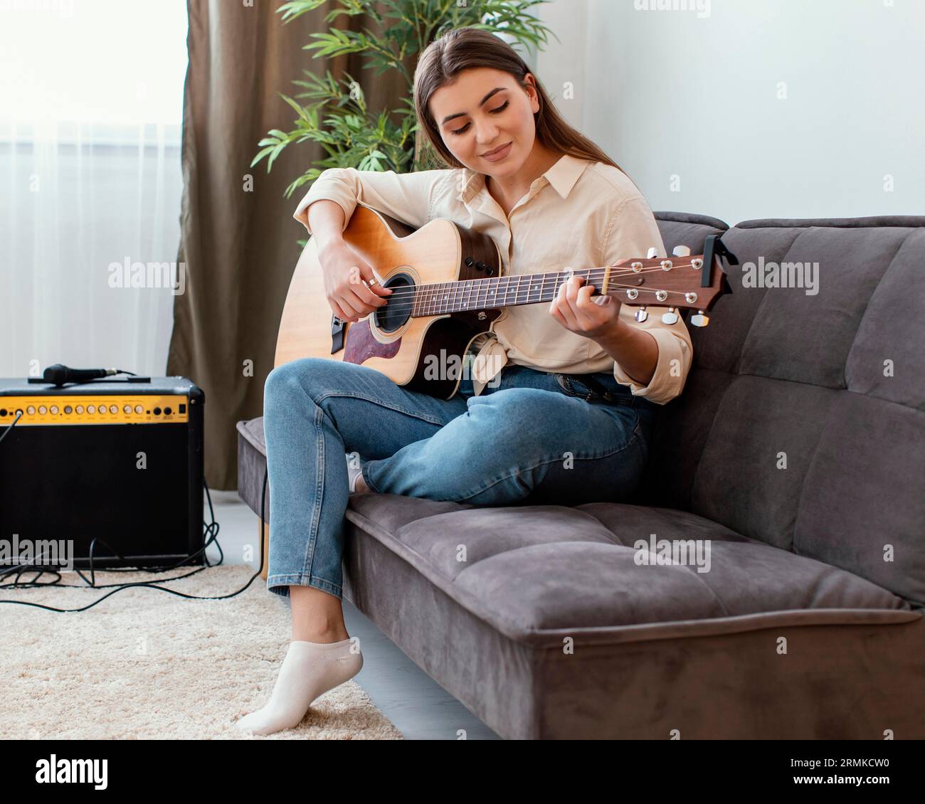 Side View Female Musician Home Playing Acoustic Guitar While Sitting side-view-female-musician-home-playing-acoustic-guitar-while-sitting