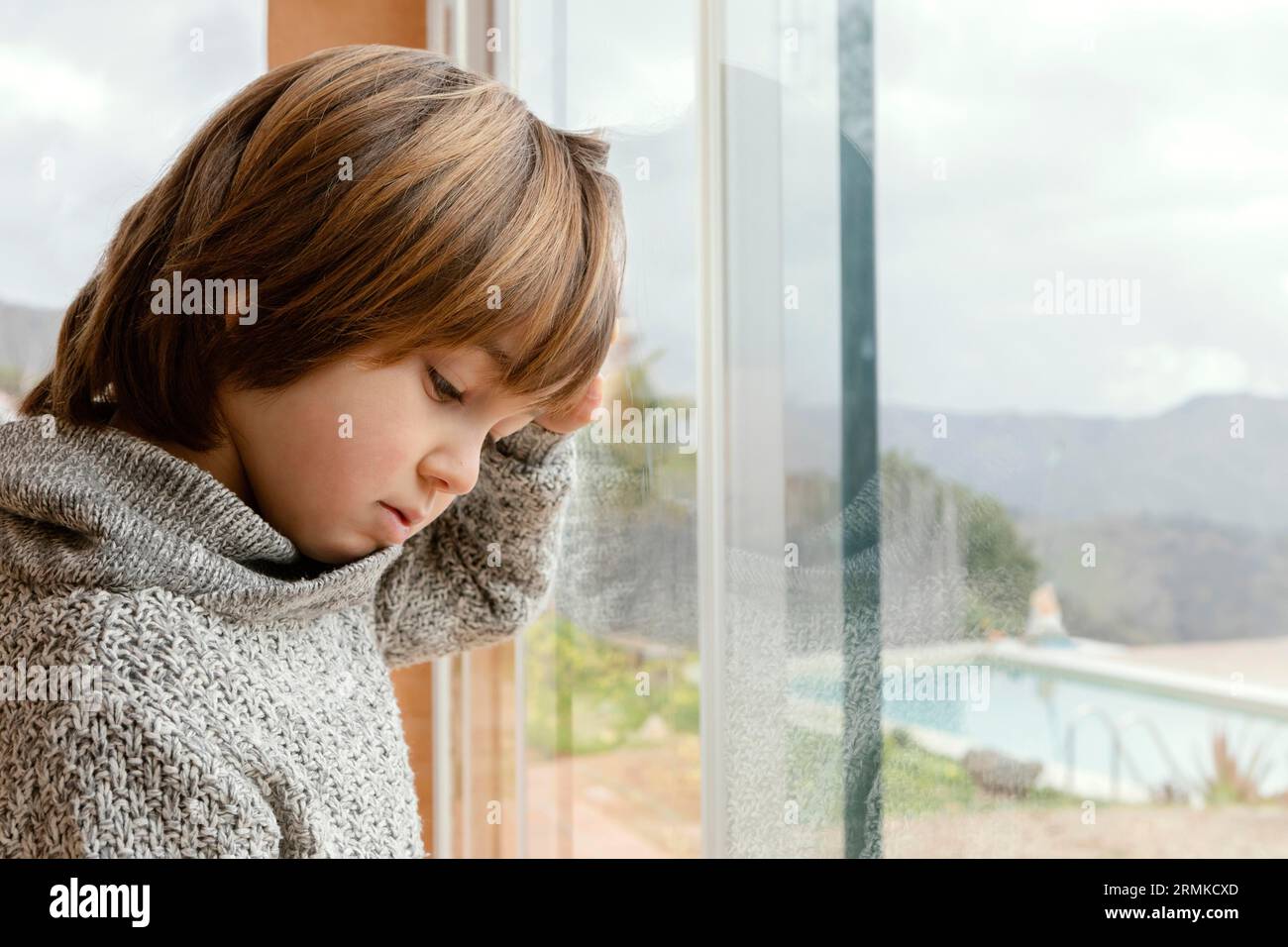 Side view sad boy standing by window Stock Photo - Alamy