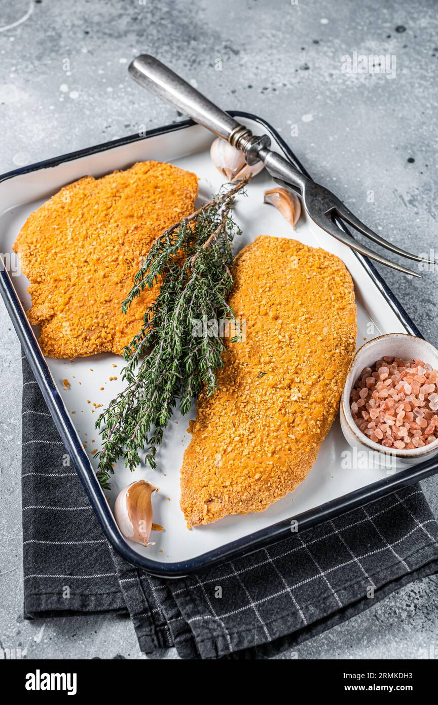 Cooking raw chicken schnitzel in breadcrumbs, uncooked meat steak. Gray ...