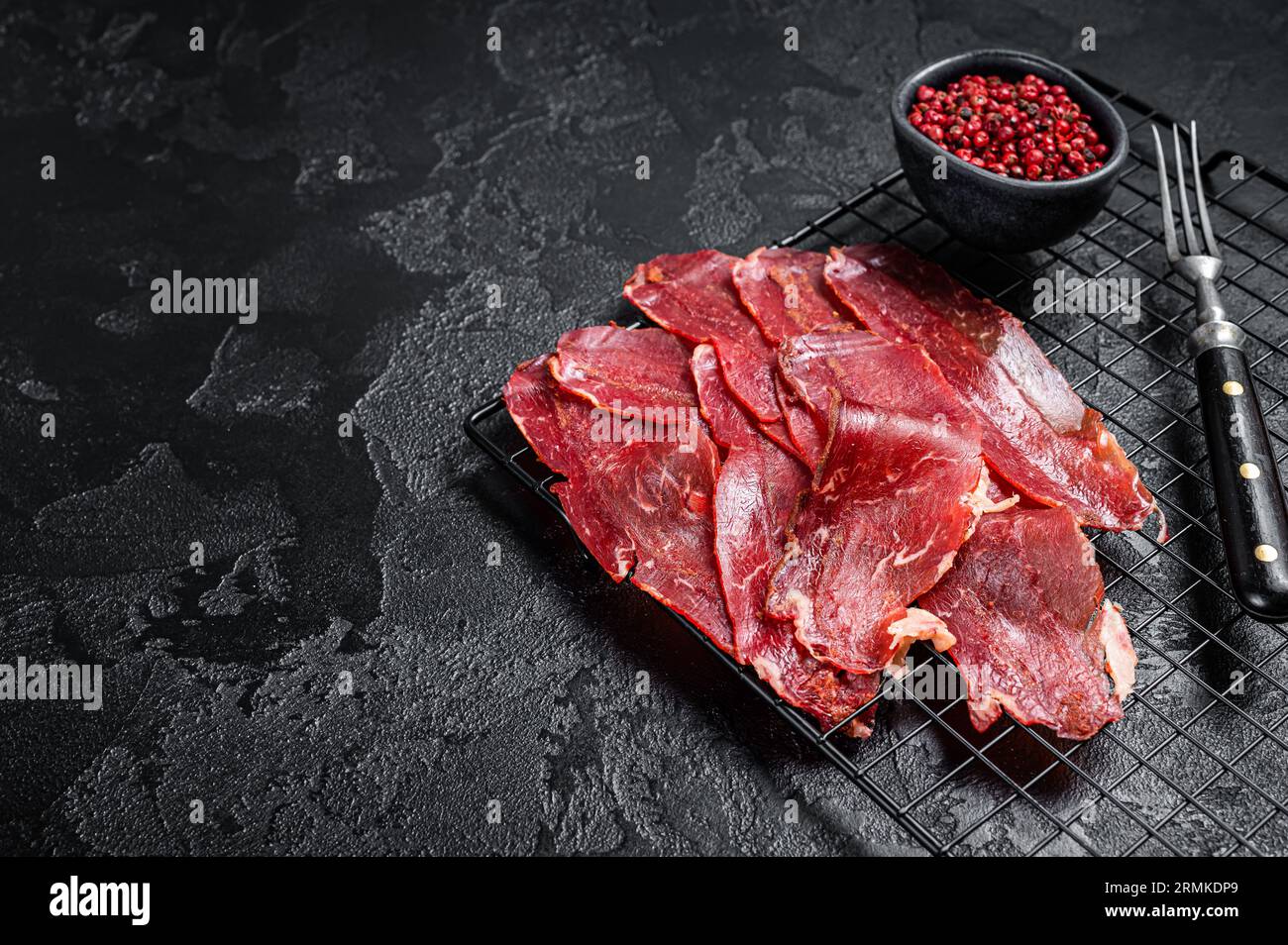Dried sliced basturma, cured beef meat ready for eat. Black background ...