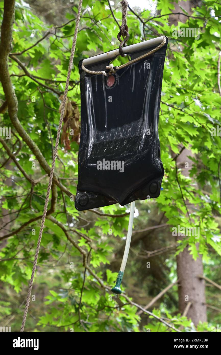 Solar warmed camp shower hanging from a tree for bathing Stock Photo ...