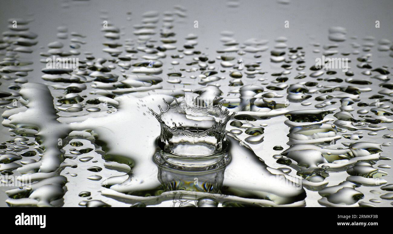 Drop of Water falling into Water against Grey background Stock Photo ...