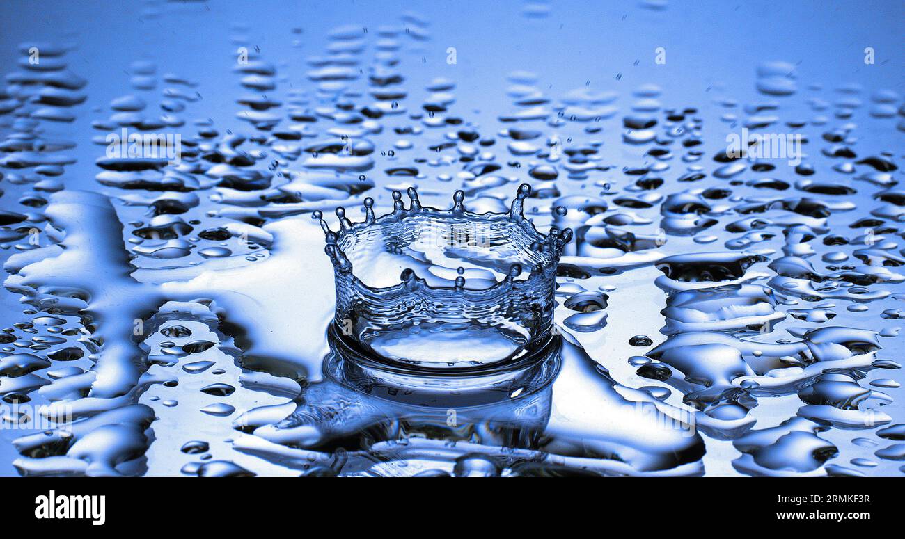Drop of Water falling into Water against Blue background Stock Photo ...