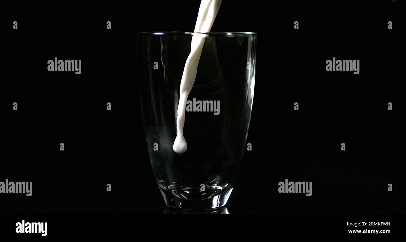 Milk being poured into Glass against Black Background Stock Photo - Alamy