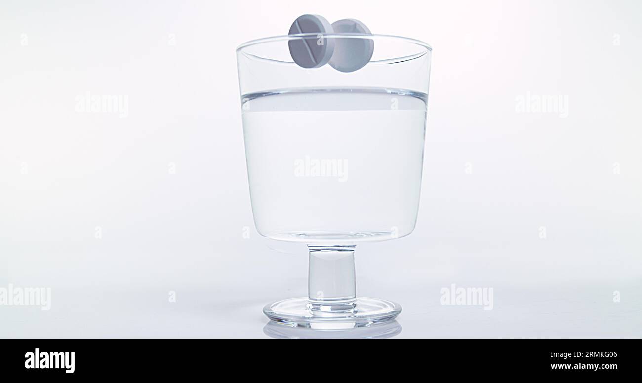 Tablets Falling and Dissolving into a Glass of Water against White ...