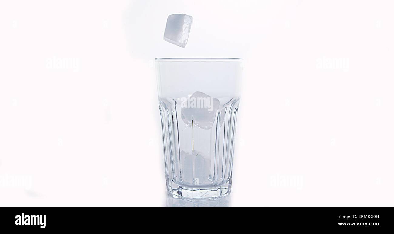 Ice Cubes Falling into Glass against White Background Stock Photo - Alamy