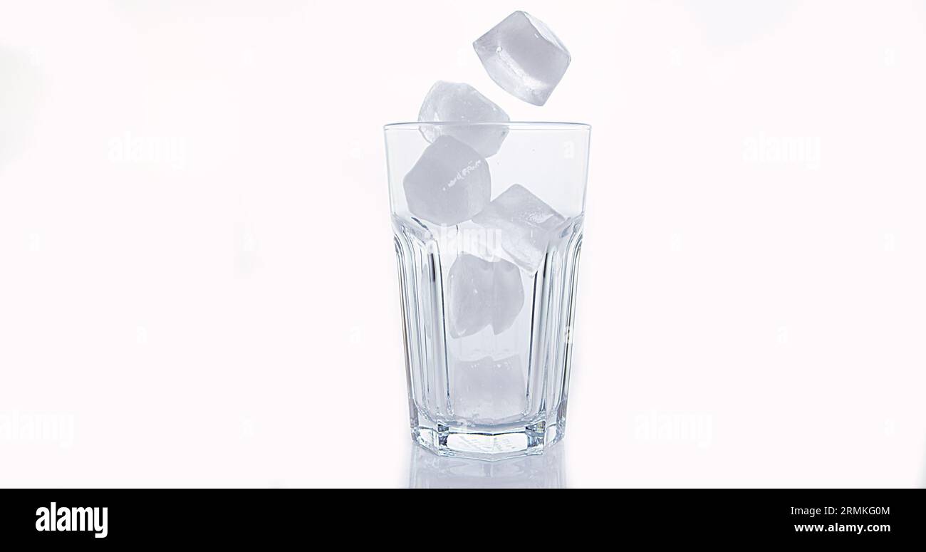 Ice Cubes Falling into Glass against White Background Stock Photo - Alamy