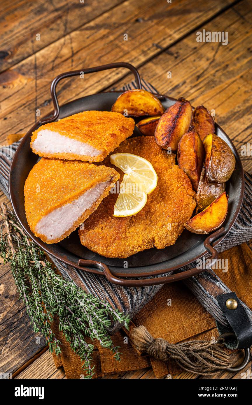 Delicious crispy pork schnitzel with fried potato wedges. Wooden ...