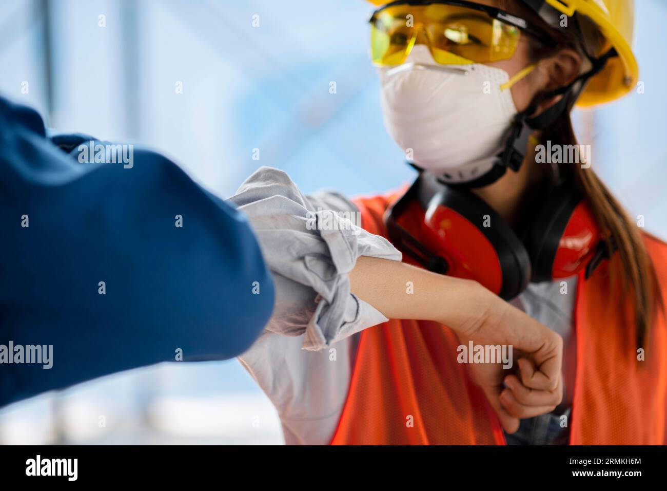 Colleagues with safety equipment touching elbow Stock Photo - Alamy