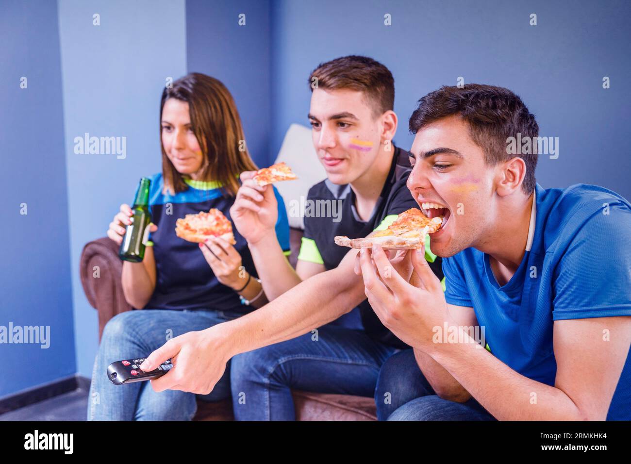 Football fans couch eating pizza Stock Photo - Alamy