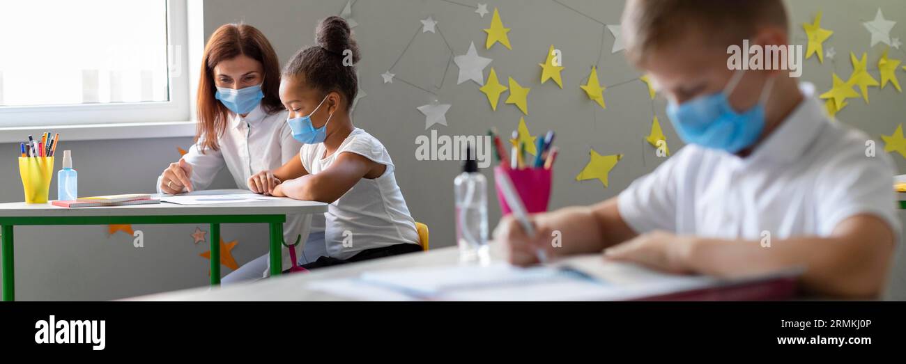 Kids teacher wearing medical masks classroom Stock Photo - Alamy