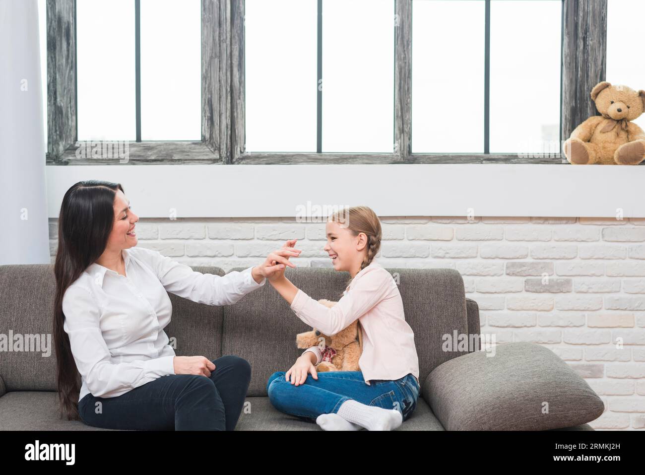 Happy female psychologist giving high five little girl sitting sofa ...