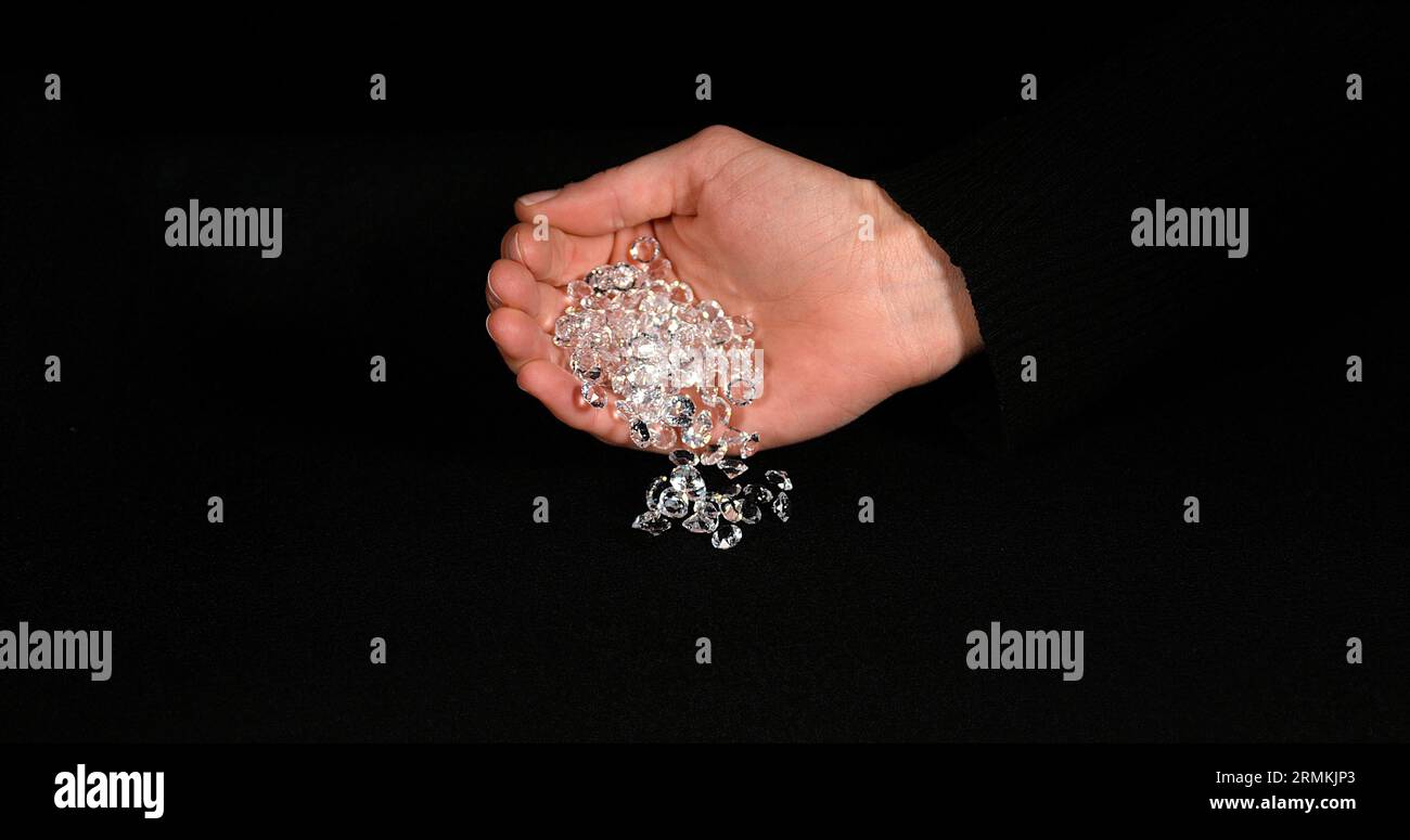 Diamonds falling into Hand against Black Background Stock Photo - Alamy